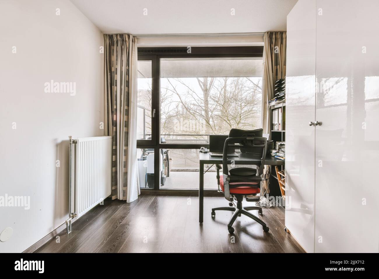 Table with computer and decoration located near big window and shelves ...