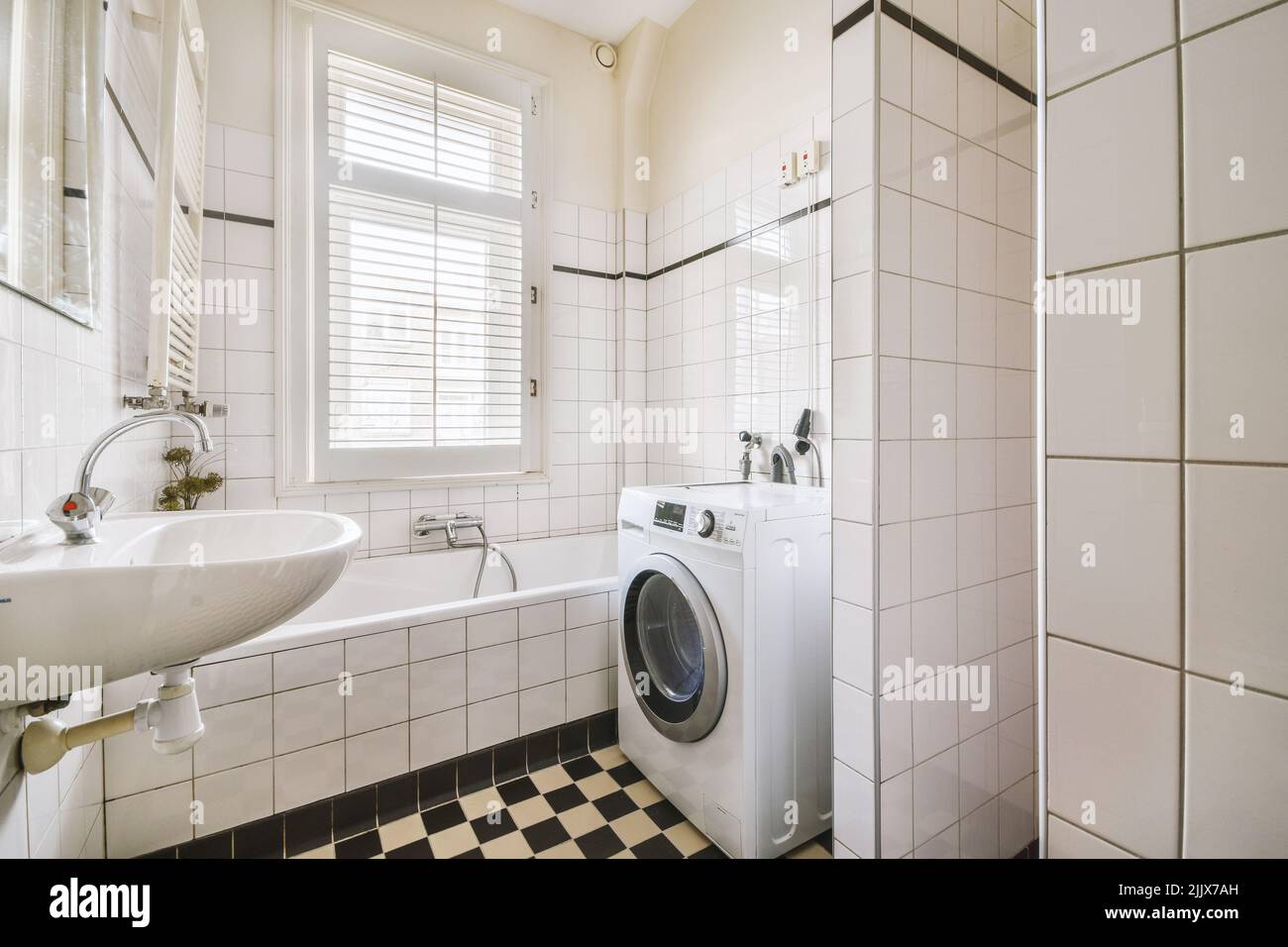 Interior of modern white tiled bathroom with washing machine bathtub ...