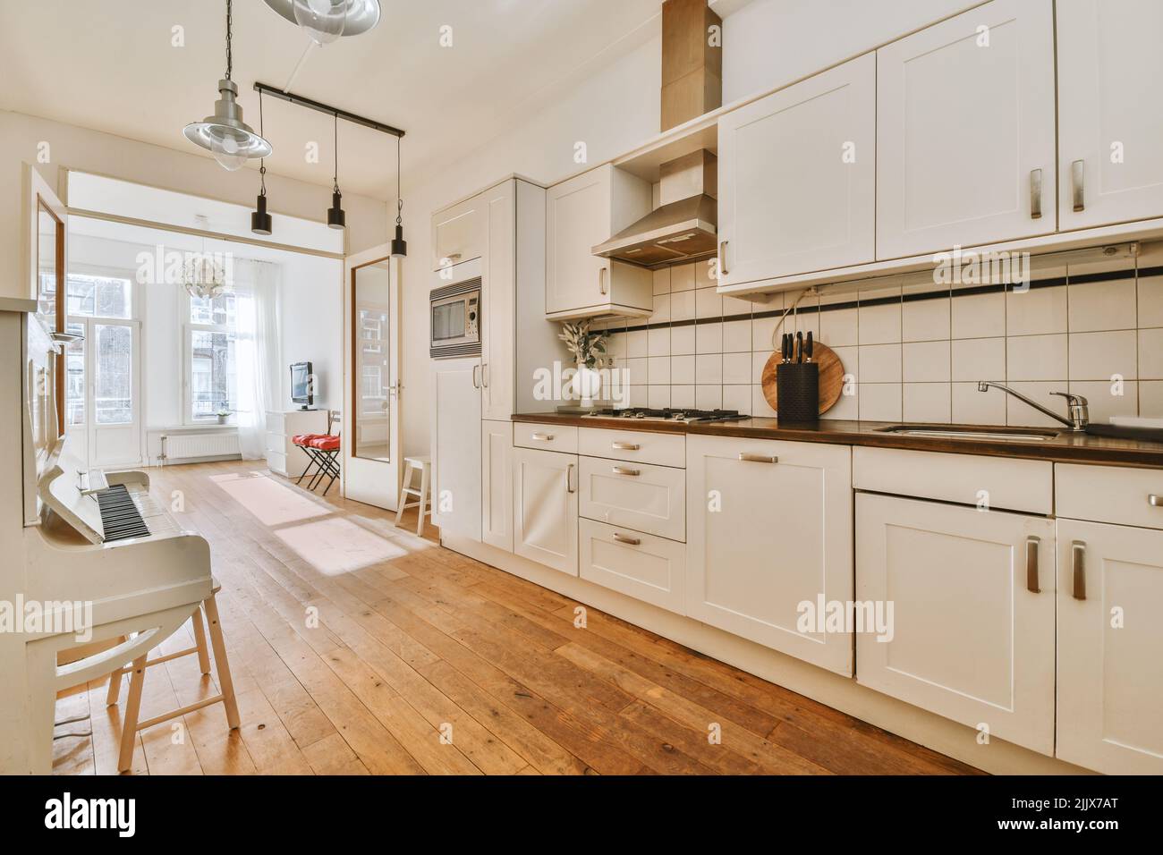Counter with white cupboards and sink near vintage piano placed in ...