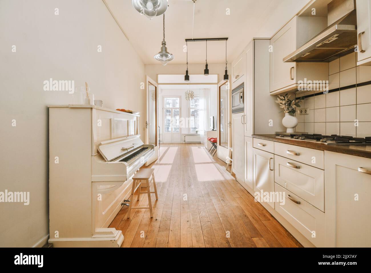 Counter with white cupboards and sink near vintage piano placed in ...