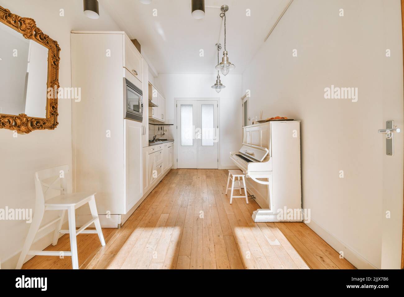 Counter with white cupboards and sink near vintage piano placed in ...