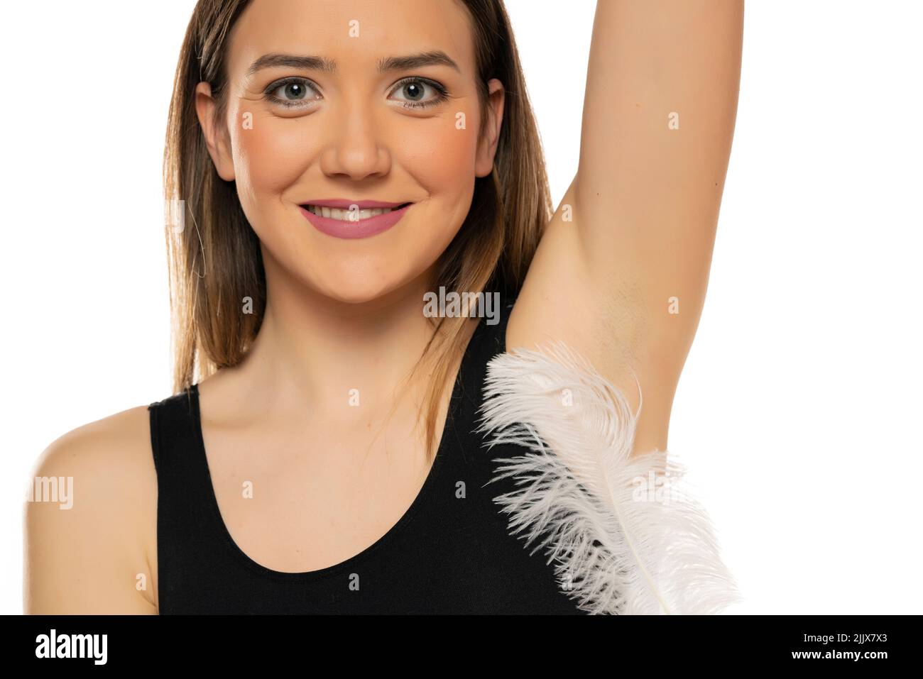 young smiling woman caressing the armpit with white feather on a white ...