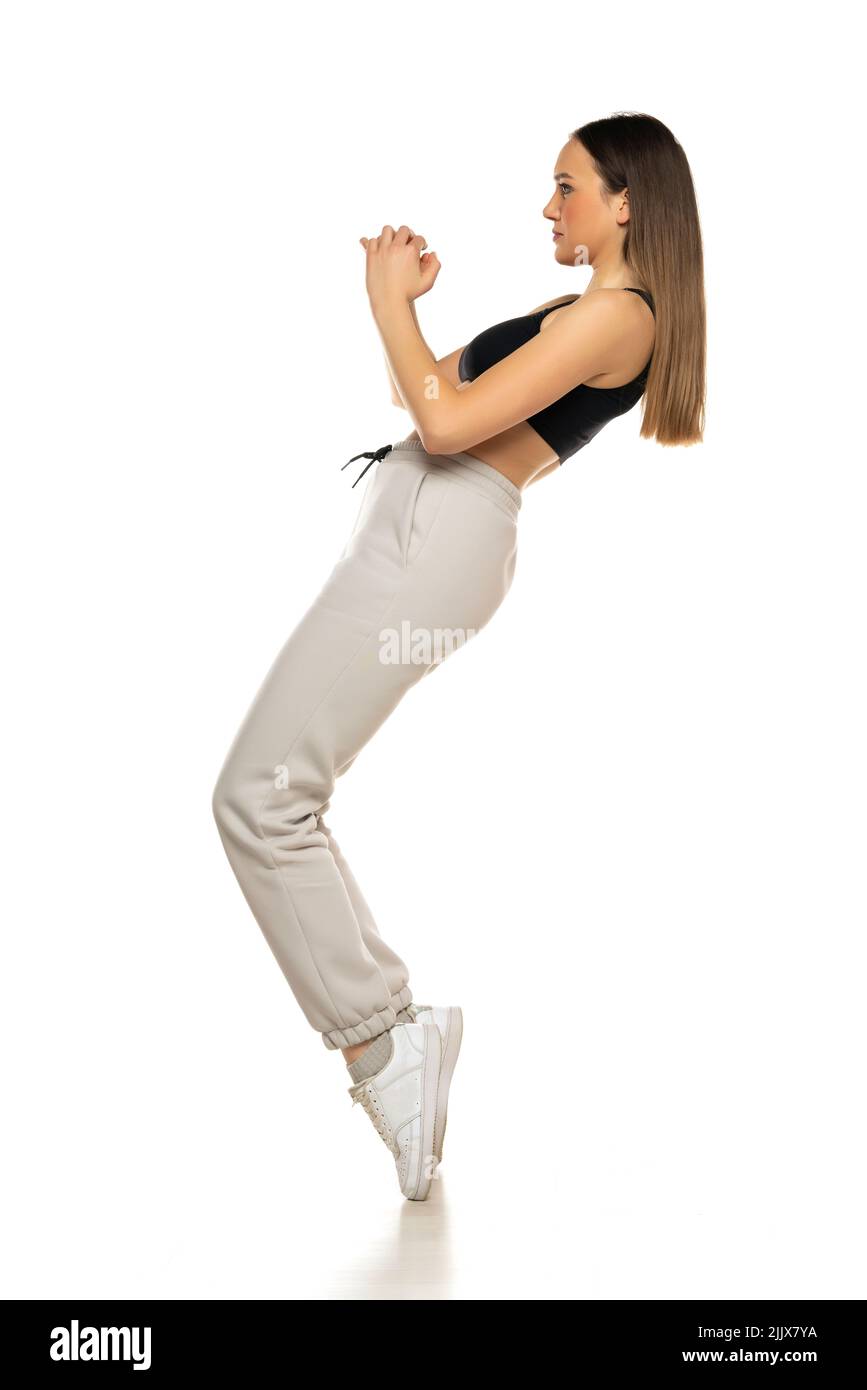a young woman in a gray tracksuit and black top poses against a white ...