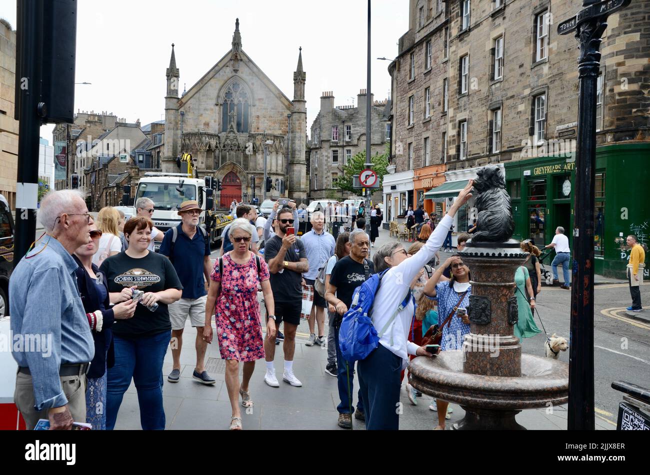 tourists with the greyfriars bobby statue touching his nose for luck ...