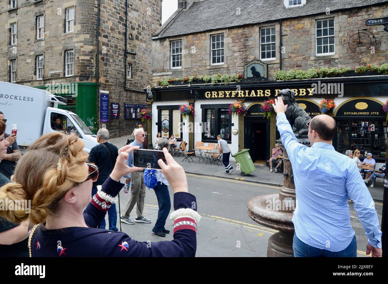 tourists with the greyfriars bobby statue touching his nose for luck ...