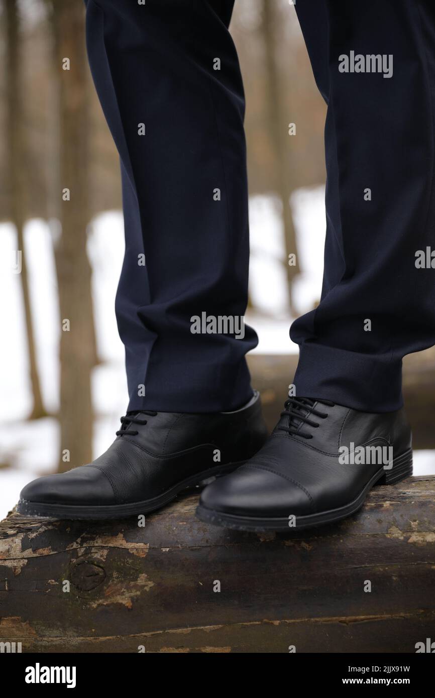 A vertical shot of male legs wearing classic pants and shoes standing ...