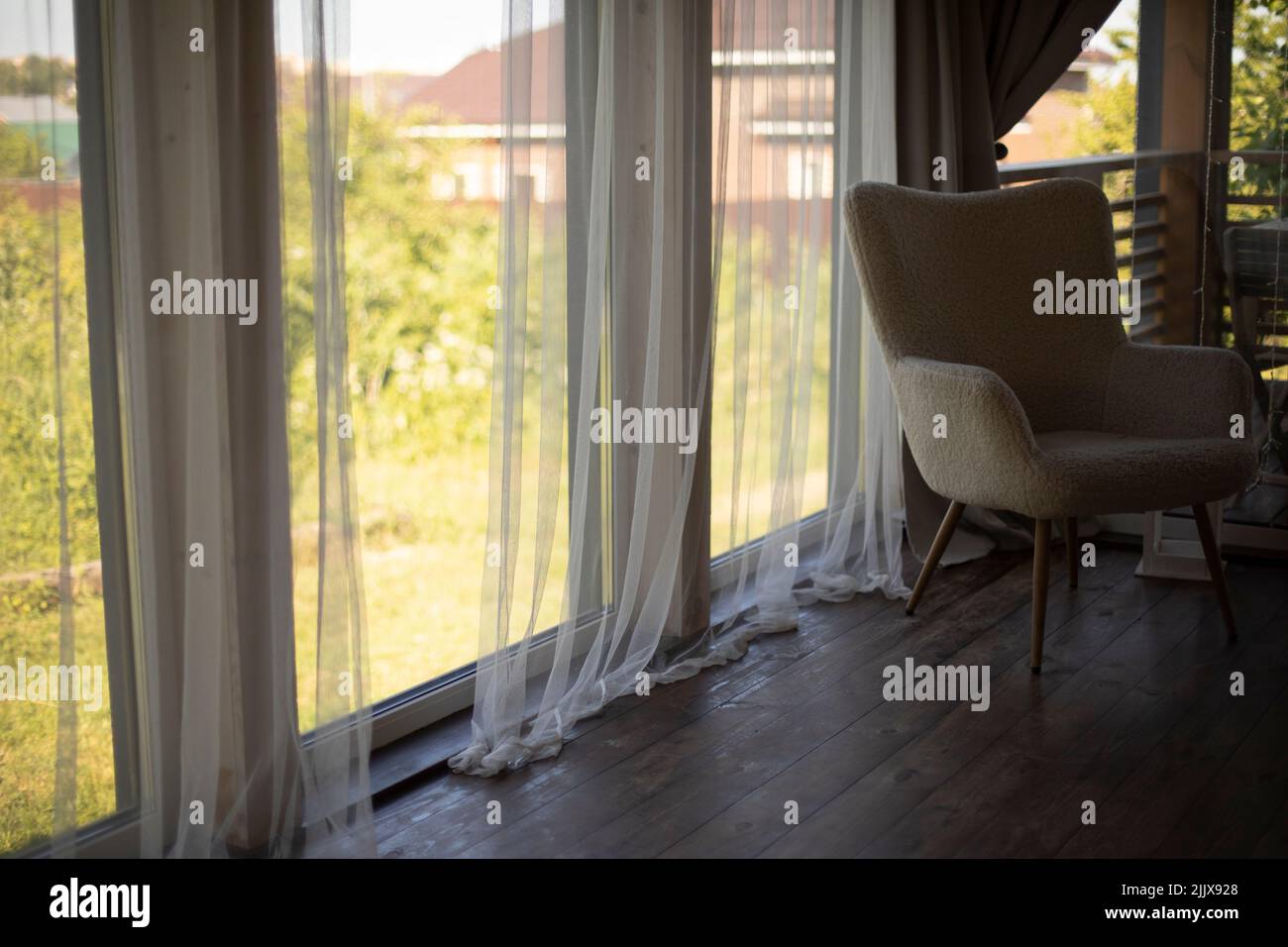 Transparent curtains on large window. Interior of room with armchair ...