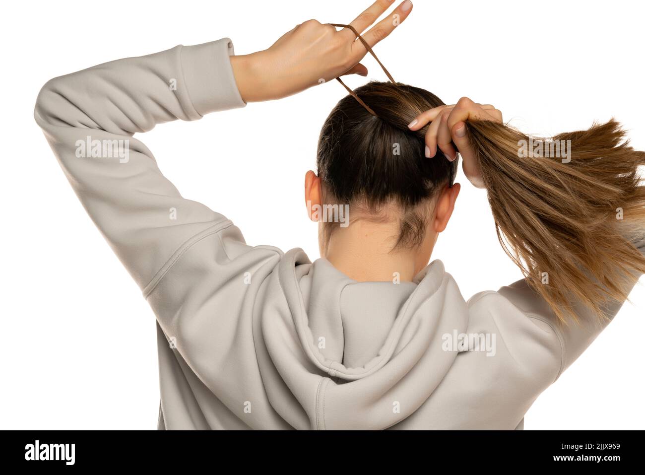 a young woman in a gray tracksuit ties a pony tail to a white ...