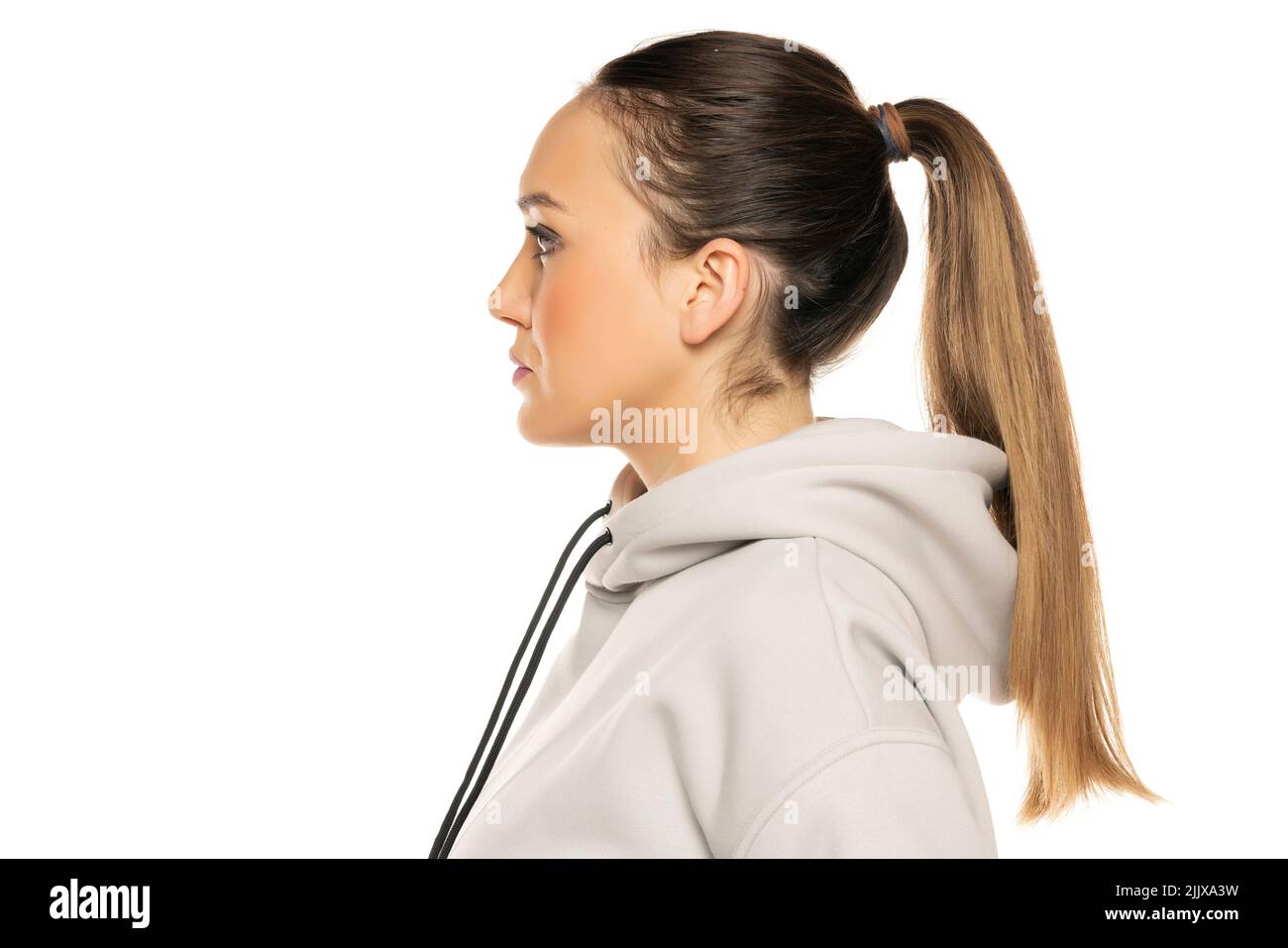 a young woman in a gray tracksuit and pony tail posing to a white ...