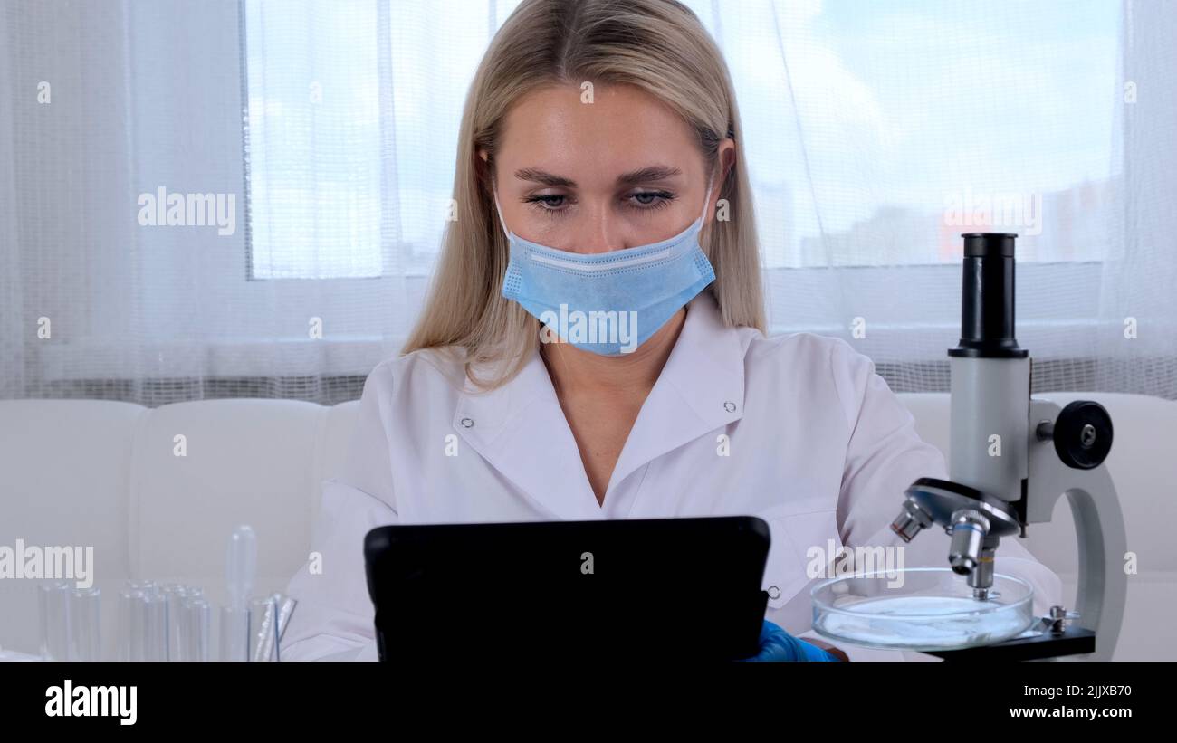 female research chemist scientist in a protective mask and gloves ...