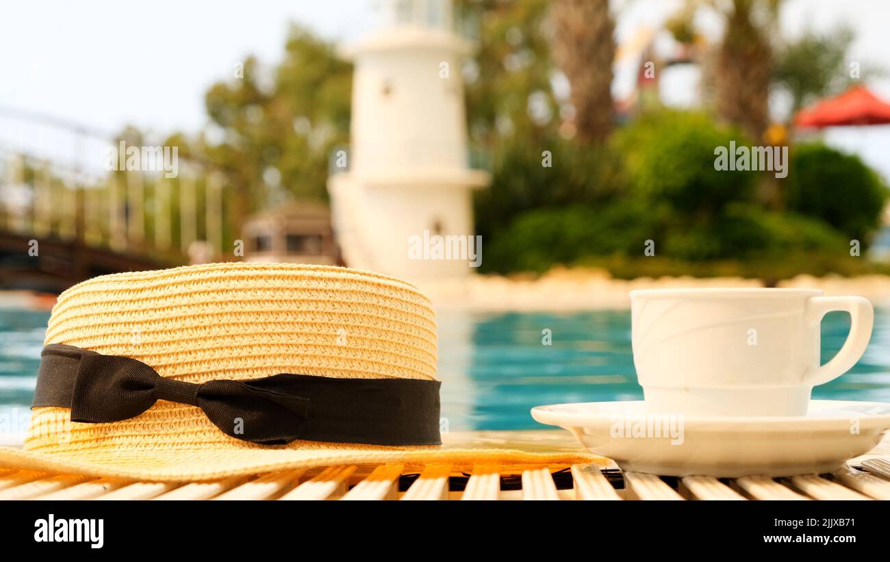 cup of coffee and a straw hat in front of a swimming pool and a ...