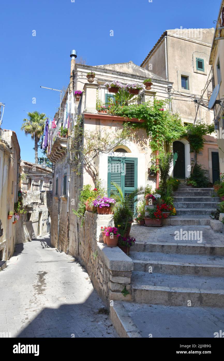 A vertical shot of narrow street between the old houses of Modica, a ...