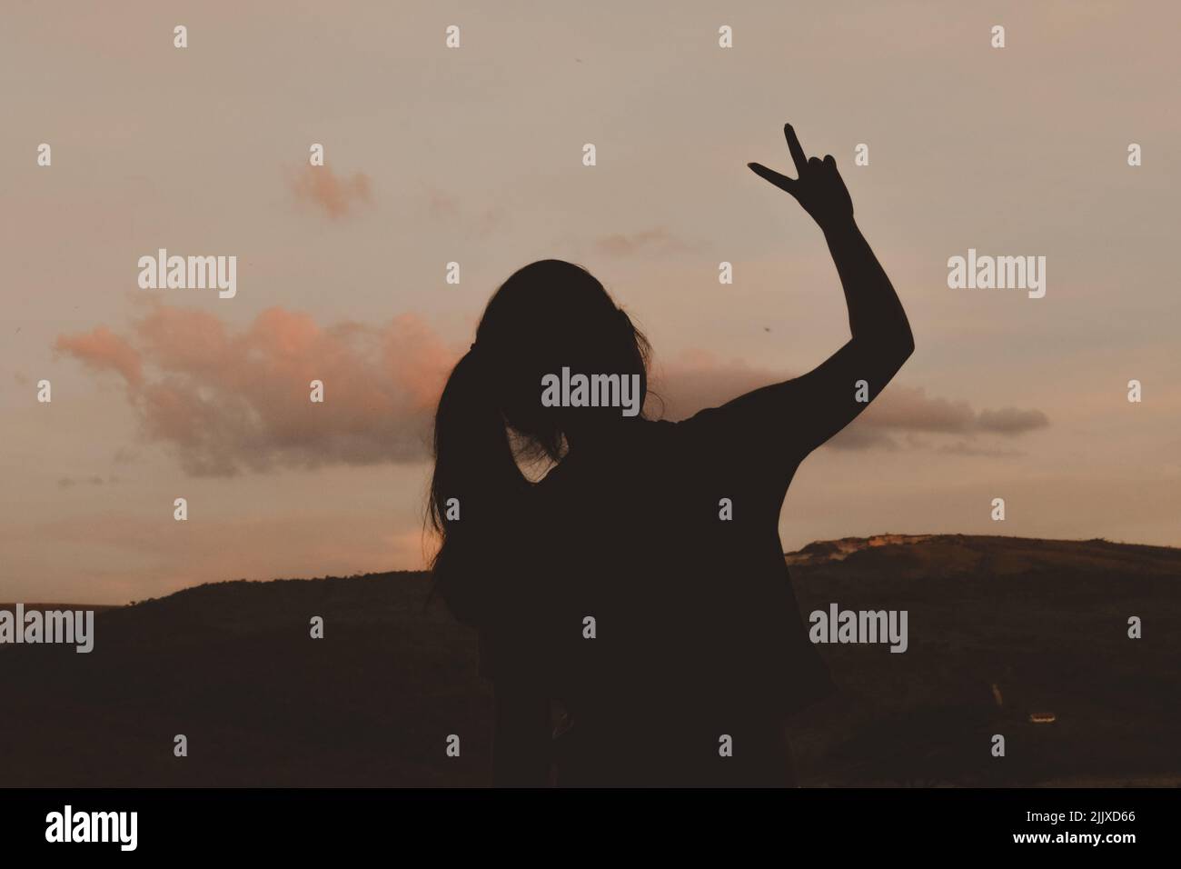 silhouette of young woman from the back making peace sign Stock Photo ...