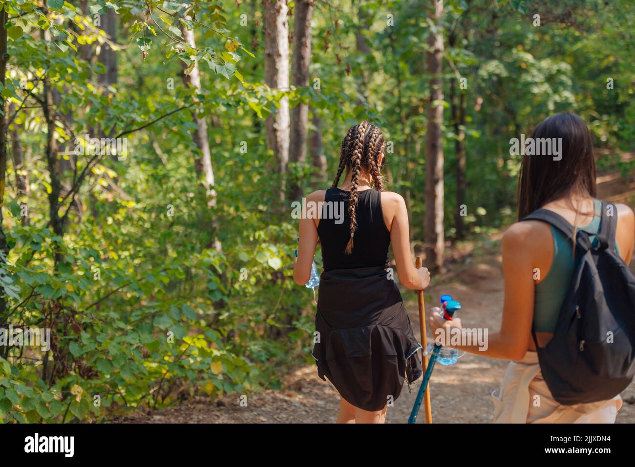 Sisters hiking through beautiful woods while wearing a backpack and ...