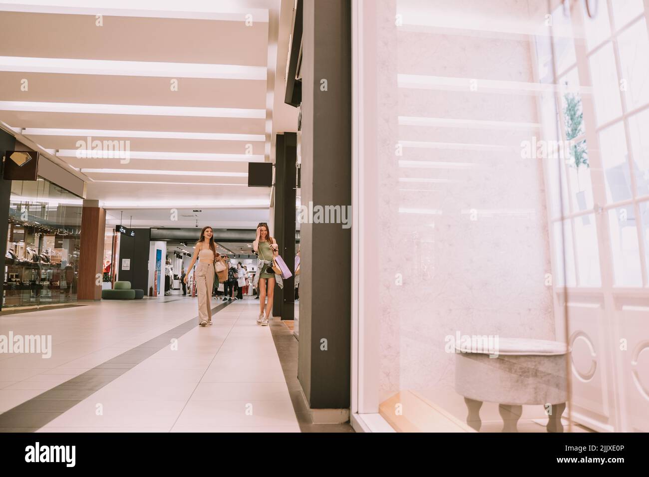Two pretty girls walking at the mall while looking at the shop windows ...