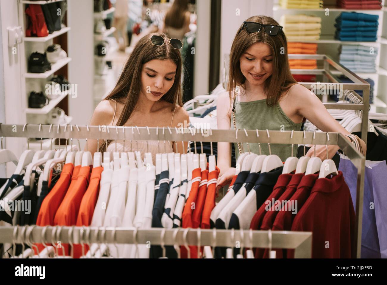Two cute and amazing girls go trough the pile of clothes in the fashion ...