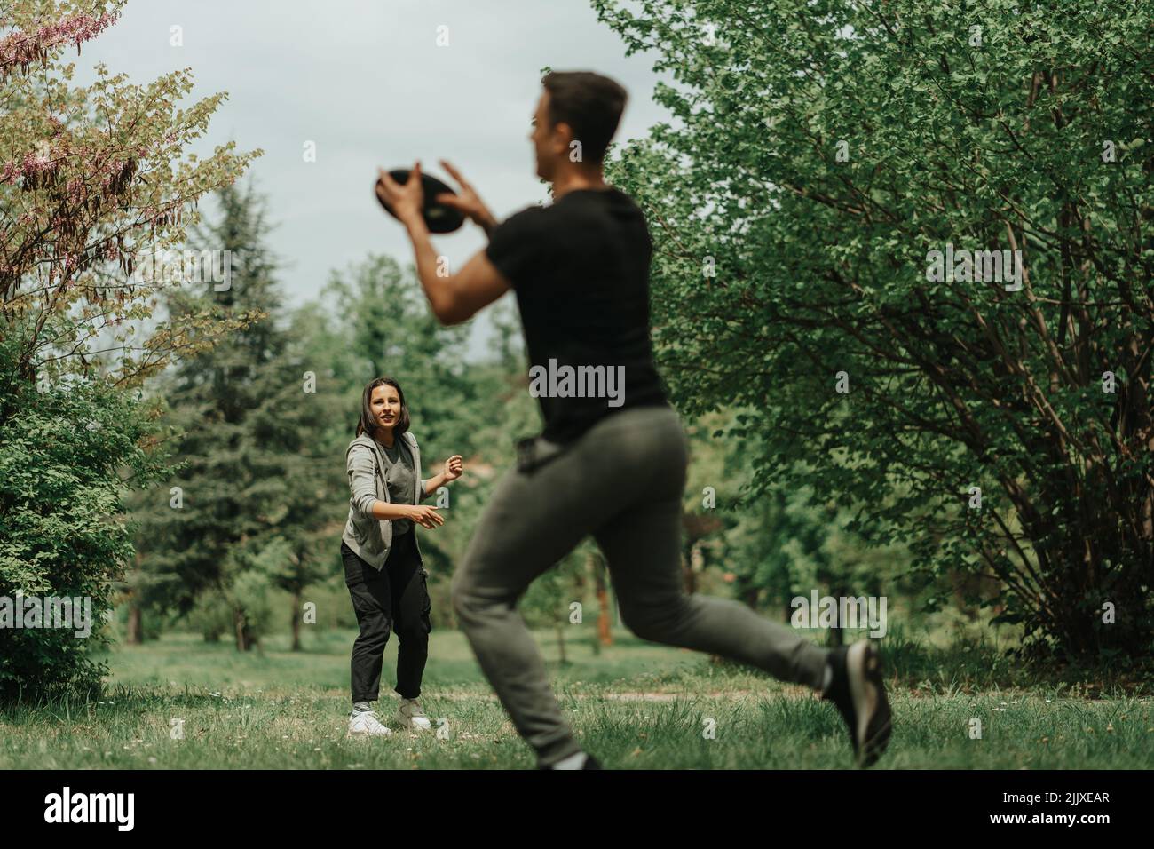 Beautiful couple playing frisbee while standing on the grass in the ...