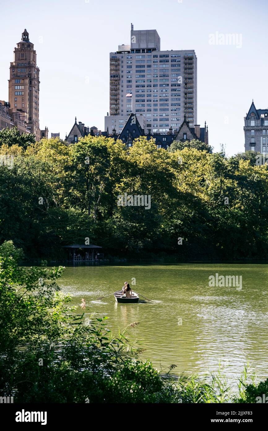 A rowboat sailing on the central park lake with the view of the ...