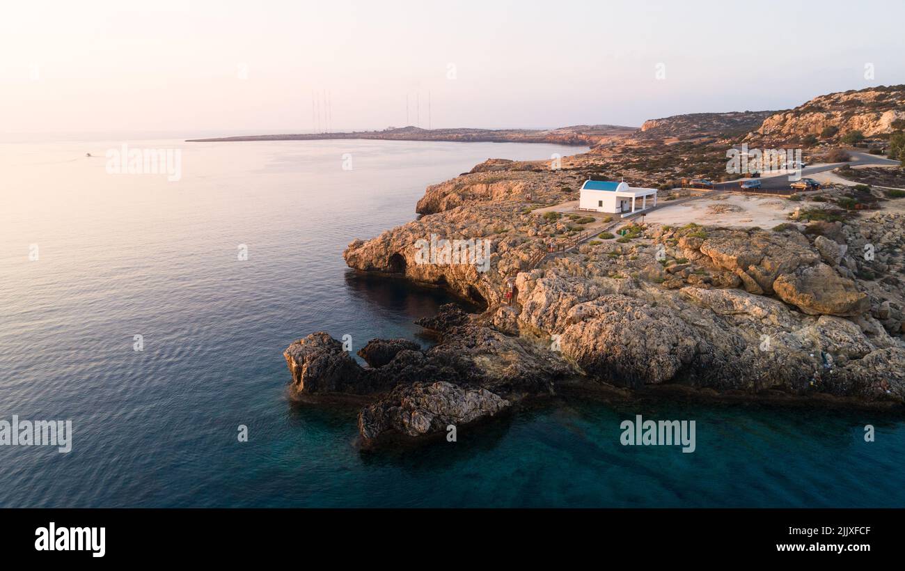 Aerial view of coastline sunset and landmark white washed chapel Agioi ...