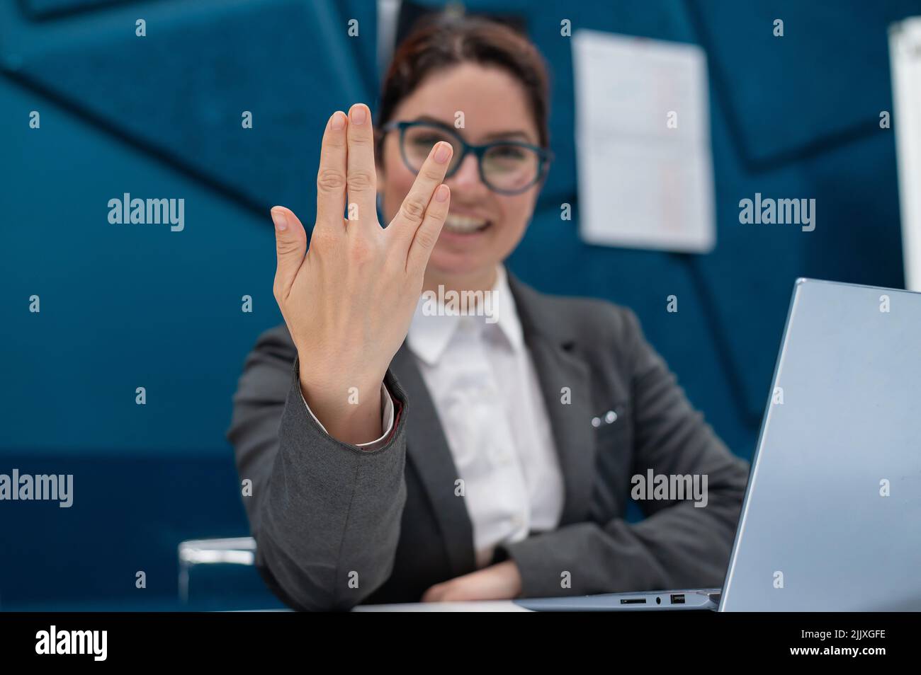 Business woman saying hello in Vulcan style while sitting at her desk ...