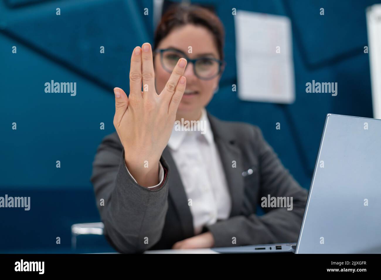 Business woman saying hello in Vulcan style while sitting at her desk ...