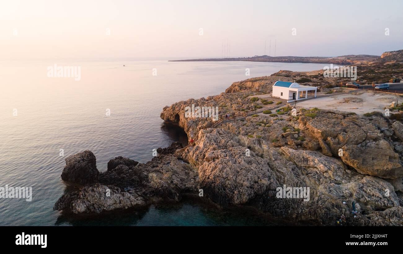Aerial view of coastline sunset and landmark white washed chapel Agioi ...