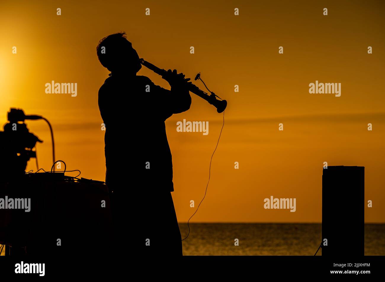 Musician in silhouette plays instruments at sunrise by the sea Stock ...