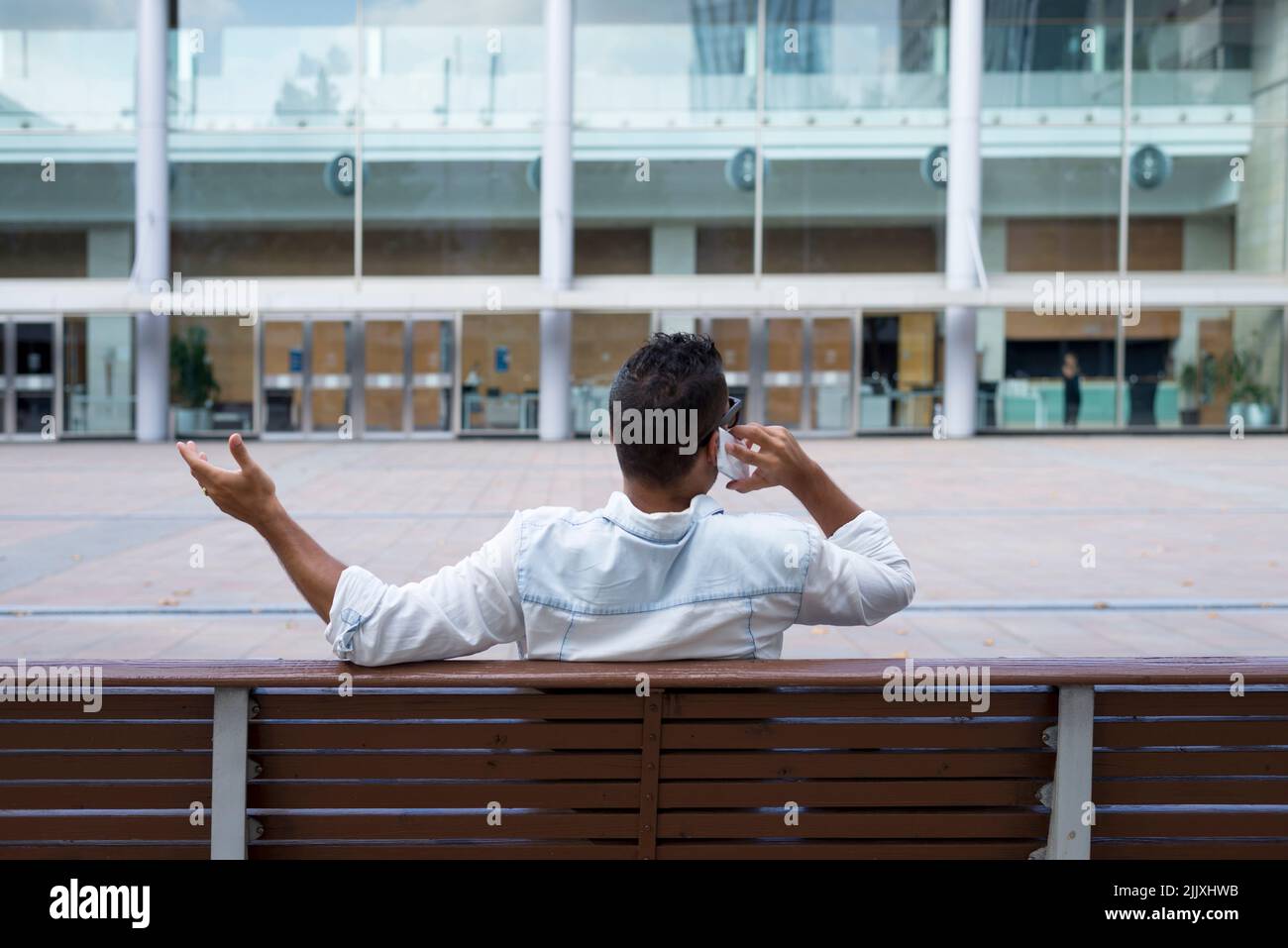 Man sitting on city bench while using phone for calling Stock Photo - Alamy