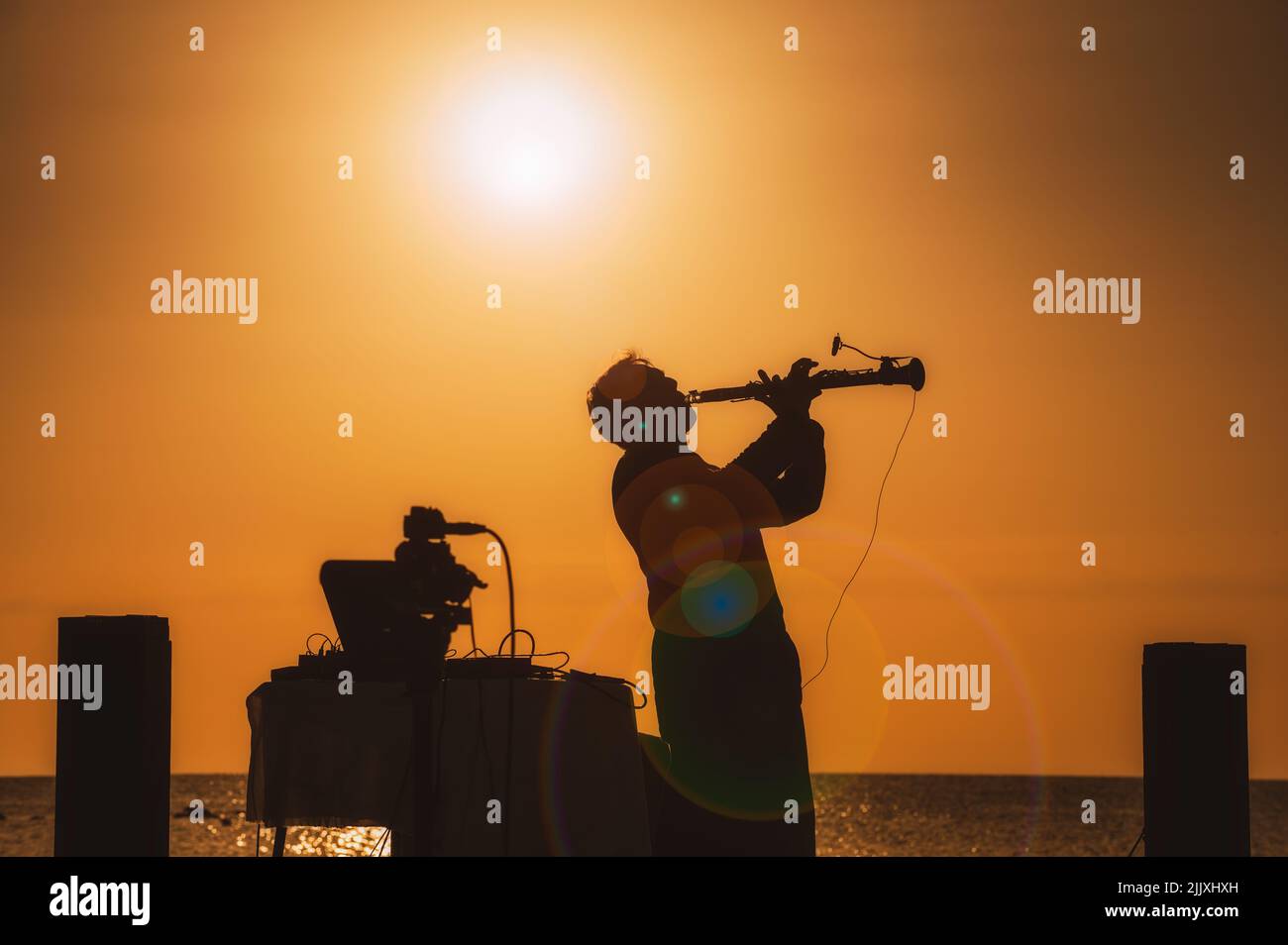 Musician in silhouette plays instruments at sunrise by the sea Stock ...