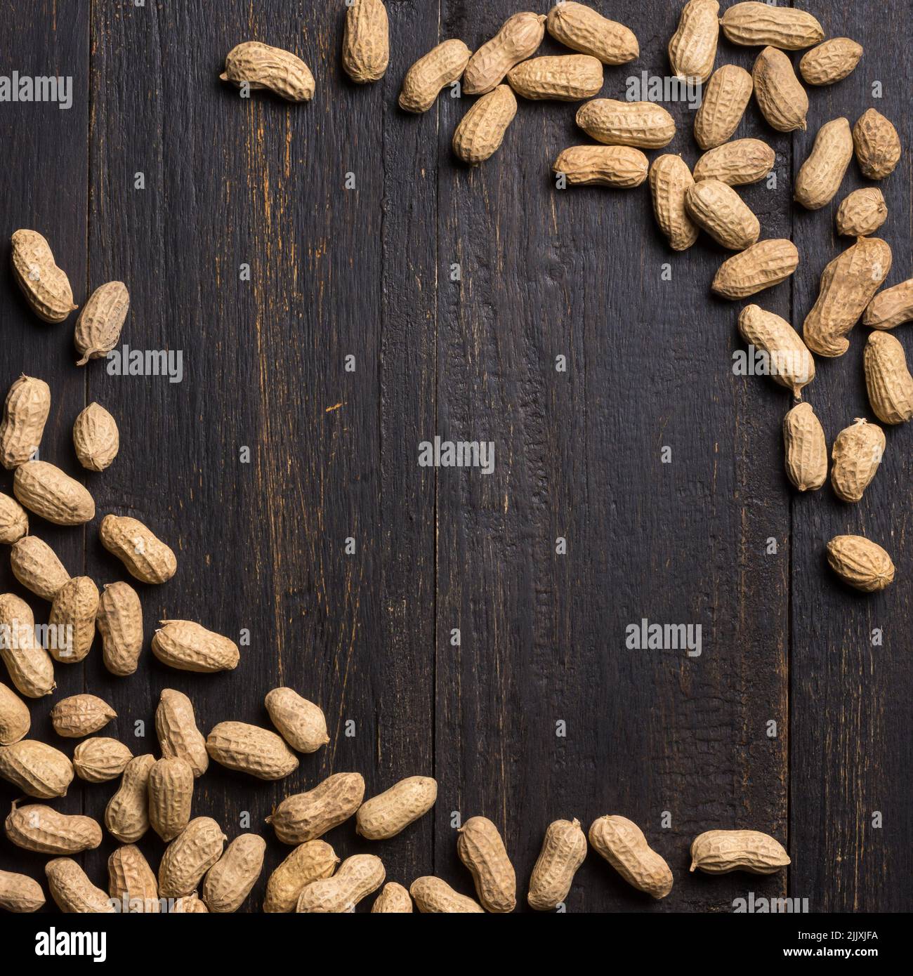 unpeeled peanuts scattered on a dark wooden background, also known as ...