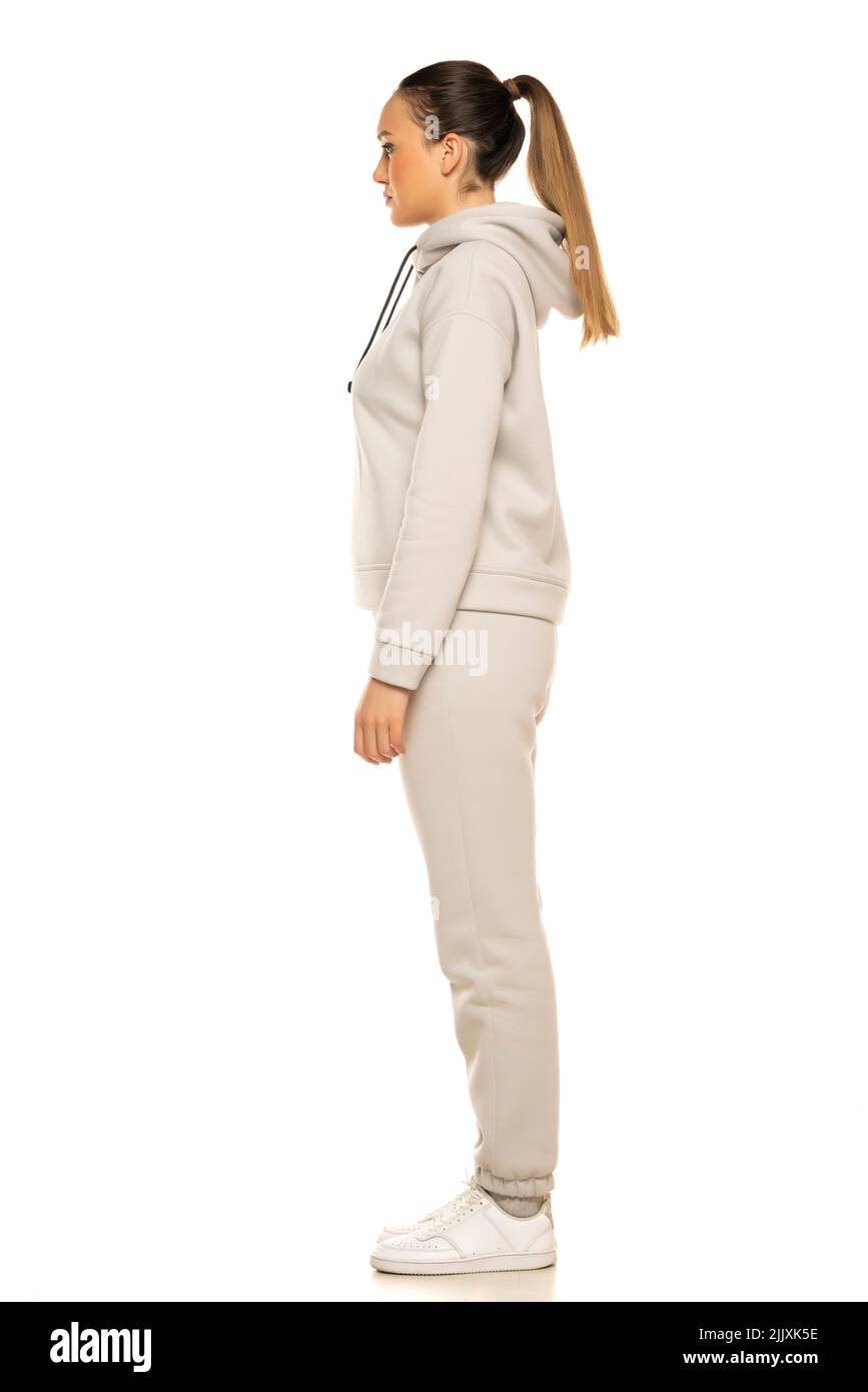 a young woman in a gray tracksuit and pony tail posing to a white ...