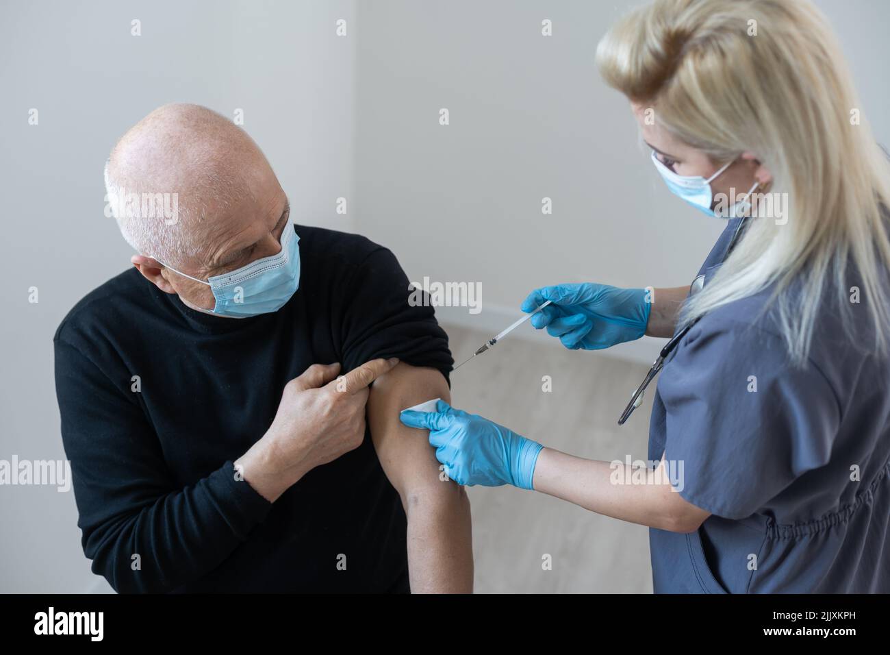 Doctor making injection to senior patient in clinic Stock Photo - Alamy