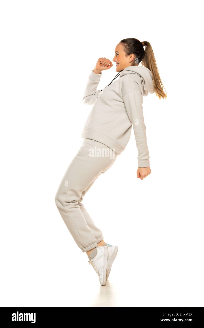 a young woman in a gray tracksuit poses against a white background in ...