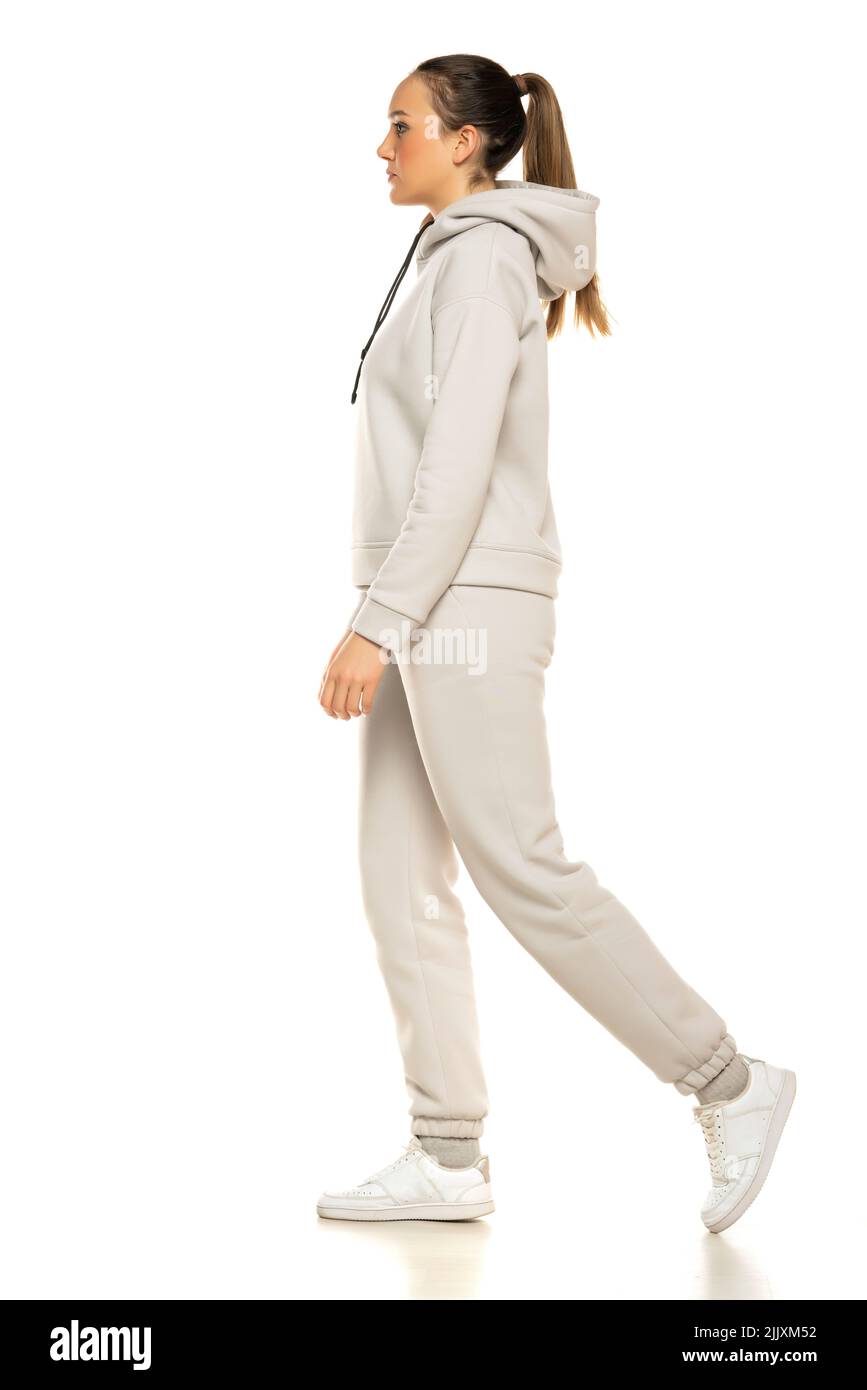 a young woman in a gray tracksuit and pony tail wakling to a white ...