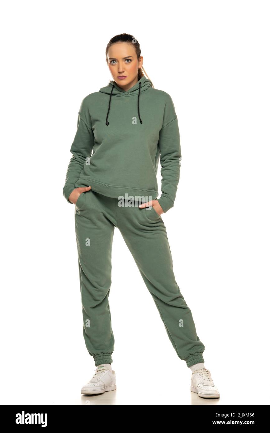 Front view of a young woman in a green tracksuit posing to a white ...