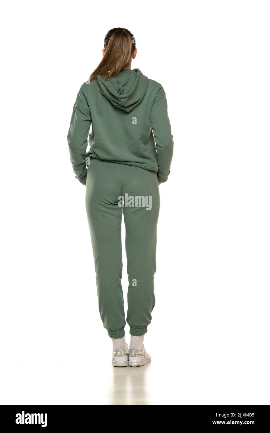 Rear view of a young woman in a green tracksuit posing to a white ...