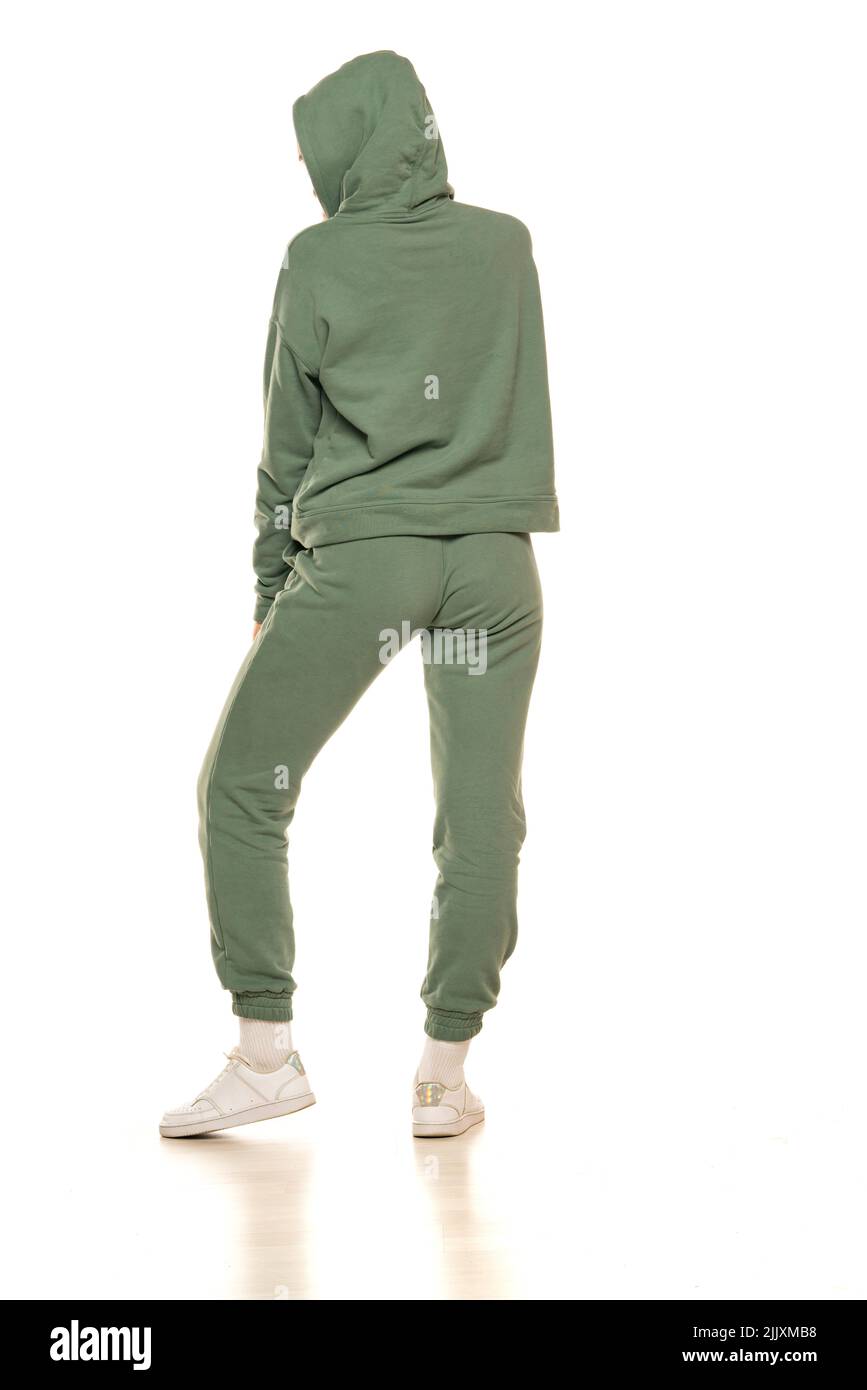 Rear view of a young woman in a green tracksuit posing and hood, to a ...