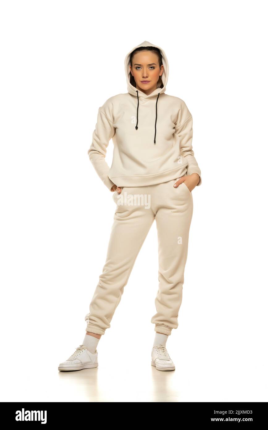 Front view of a young woman in a beige tracksuit with hood posing to a ...