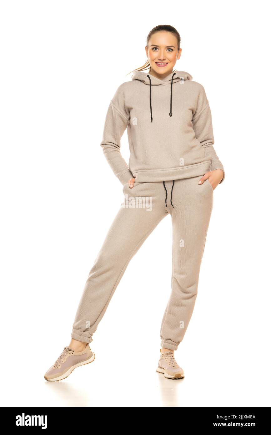 Front view of a young smiling woman in a gray tracksuit posing to a ...