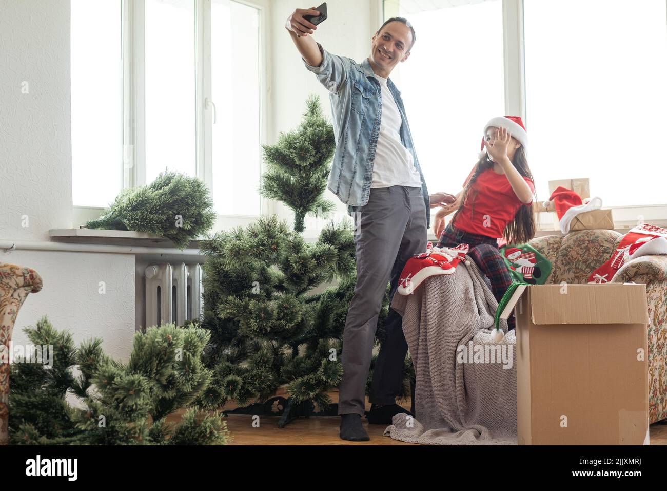 Father and little daughter decorating Christmas tree in room Stock ...