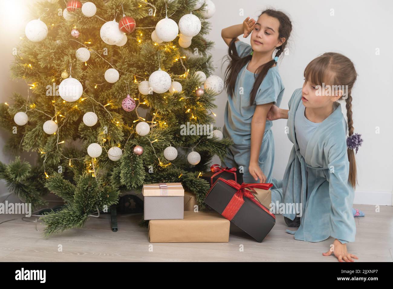 Two cute little girls under Christmas tree. Children under Christmas ...
