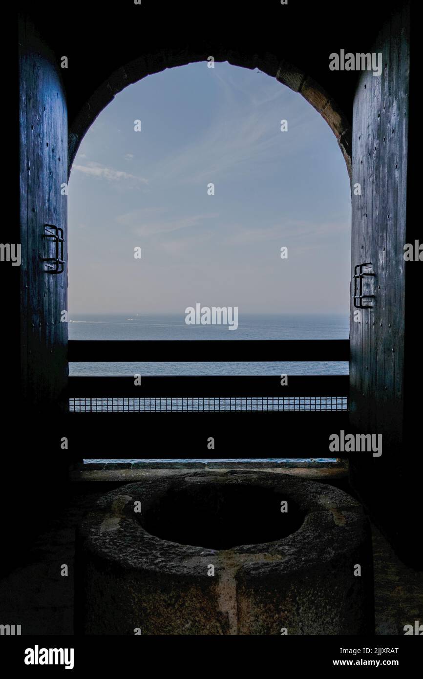 Closeup of old stone well at arched window of castle, overlooking the ...