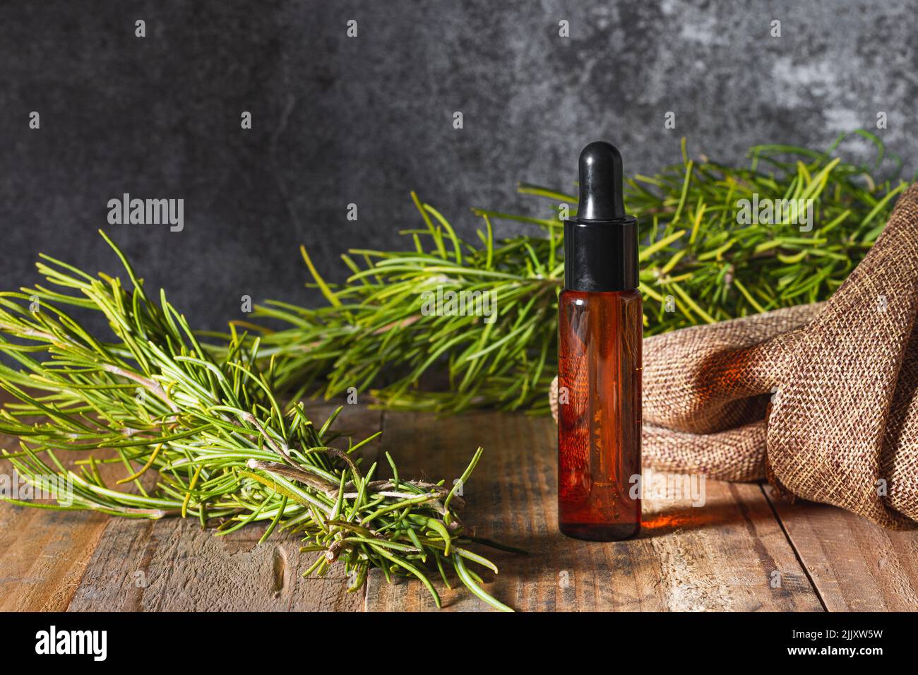 On a table of wooden planks is a brown glass bottle, with a dropper ...