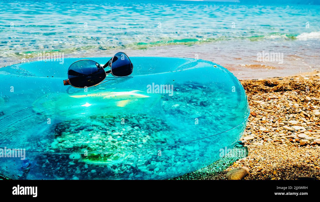 Blue inflatable swim ring float and sunglasses on the beach Stock Photo ...