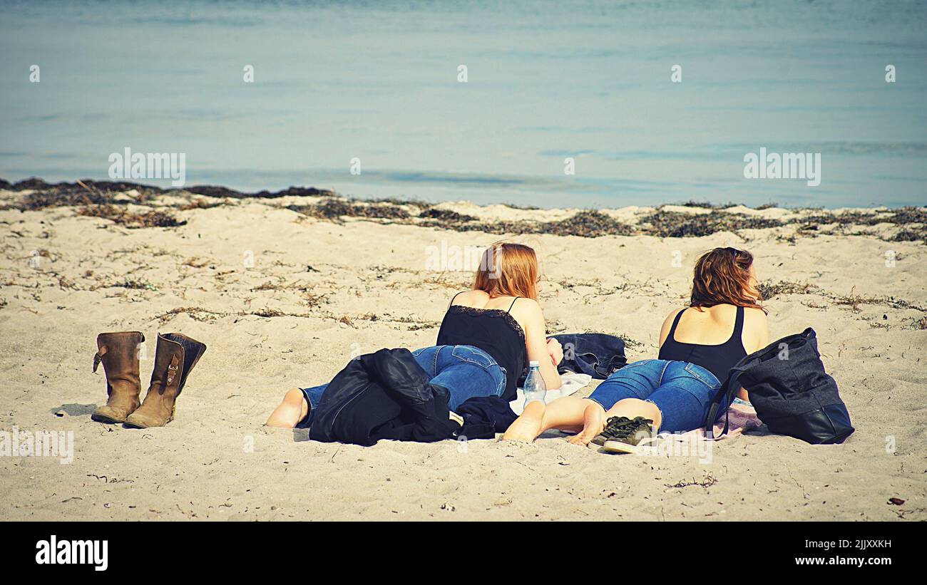 A pair of female friends with their shoes off laying and relaxing on a ...