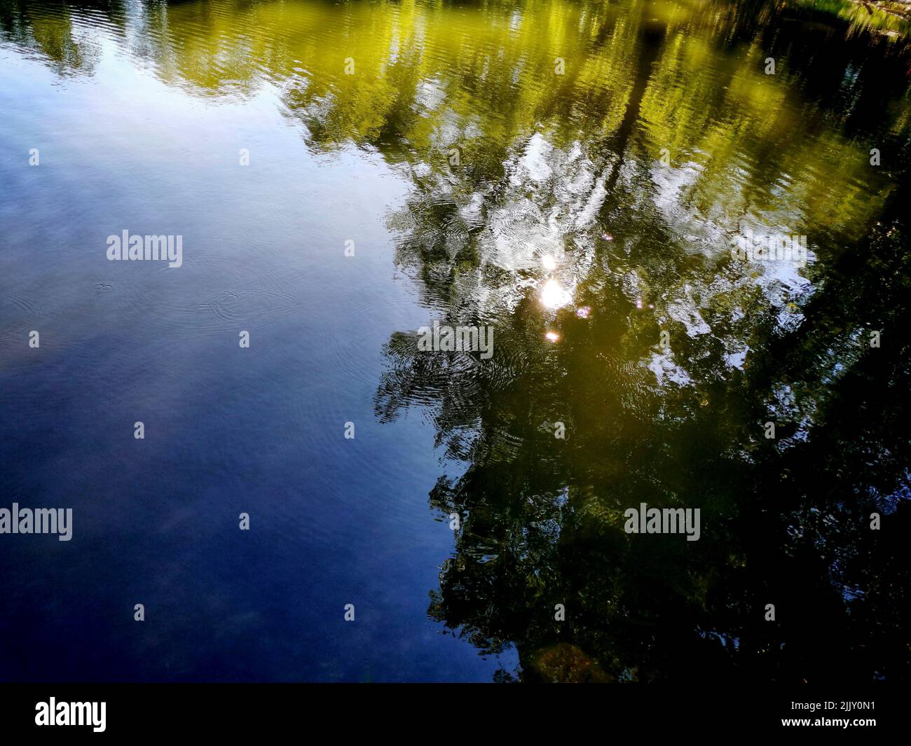 The reflection of green trees on the blue clear water Stock Photo - Alamy