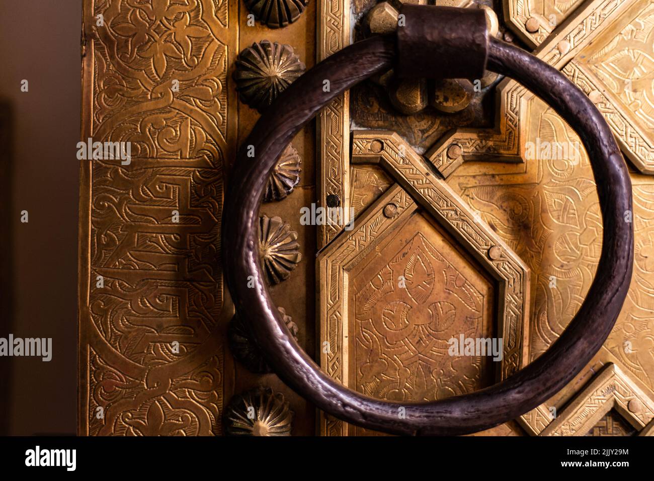Old golden door with Arabian style sculpture script with an iron ring ...