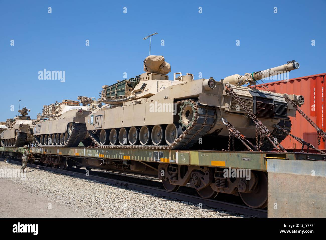 A railcar loaded with M1A2 Abrams Main Battle Tanks is inspected by a ...