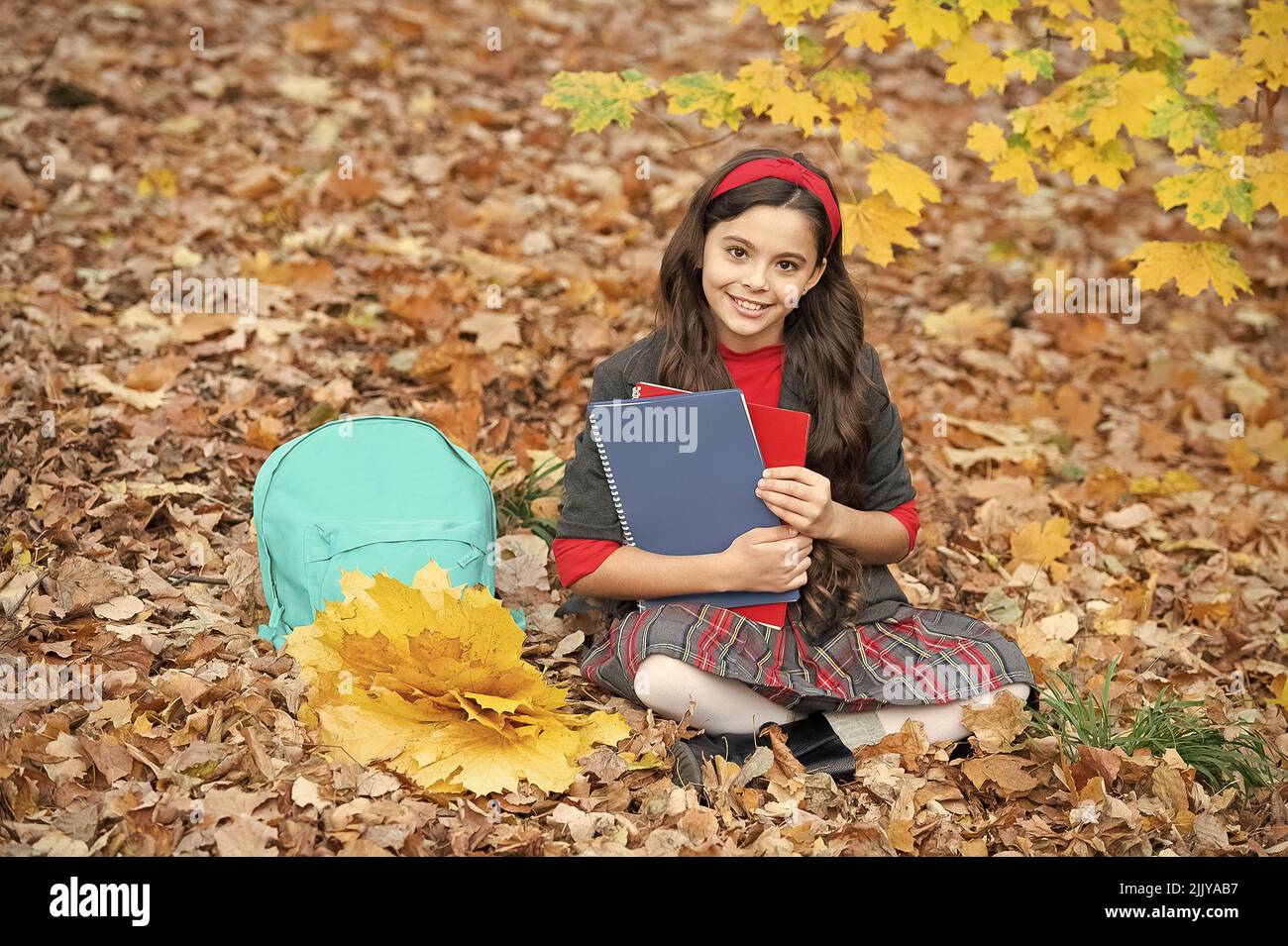 happy child with maple leaf bunch and backpack outdoor. autumn nature ...