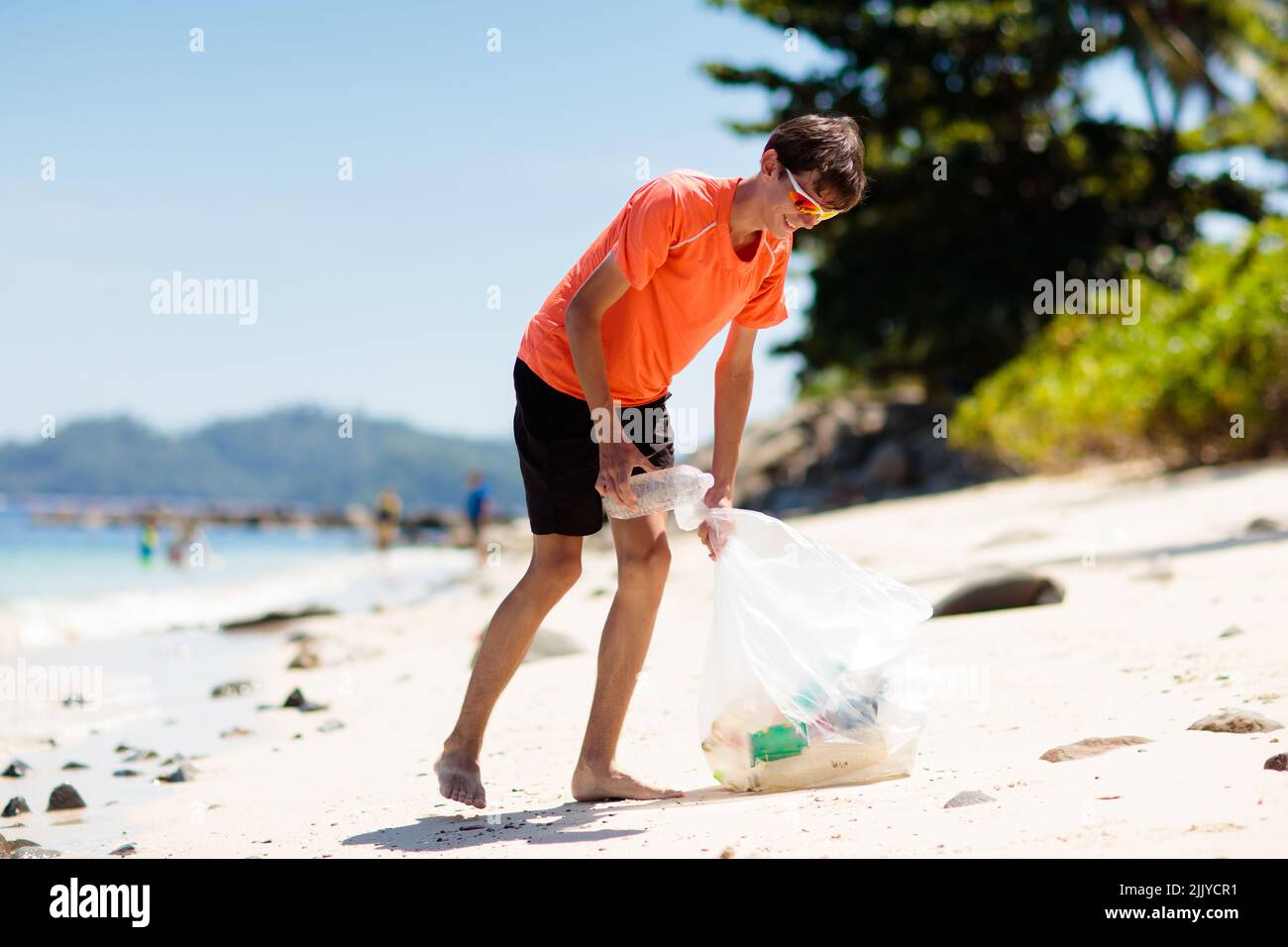 Plastic garbage. Sea and ocean pollution. Beach clean up. Young man ...